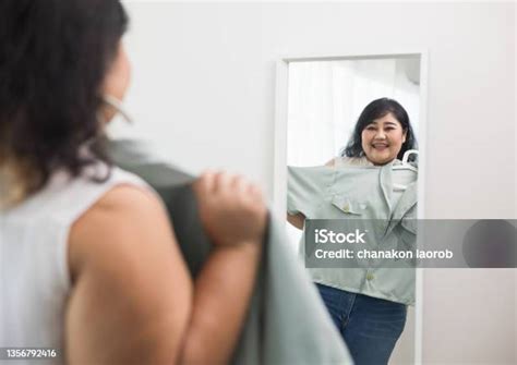 몸에 긍정적 인 플러스 크기 여성 의류 몸에 긍정적 인 플러스 크기 여자는 행복하게 집에서 거울을보고 자랑스럽게 생각합니다 크기를 측정하는 옷을 입어보십시오 고객에 대한