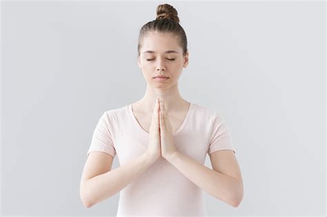 연습 요가 명상 나 마스 테 Mudra에 손바닥을 함께 들고 조용 편안 하 고 평화로운 회색 배경에 고립 된 분홍색 티셔츠에
