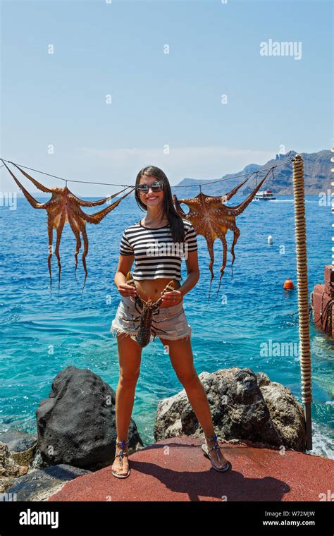 Junge Frau hält in den Händen von Hummer auf dem Hintergrund des Meeres und der Oktopus auf