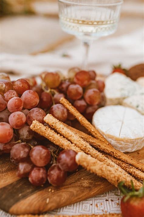 Photo Of Person Pouring Wine Into Glass Besides Some Cheese Pairings