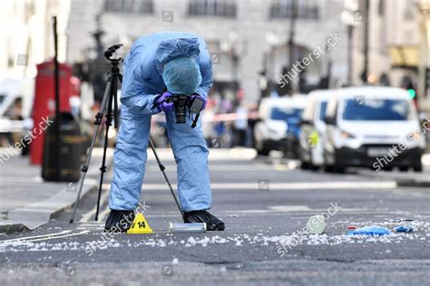 Forensic Police Officer Photographing Evidence Following Editorial