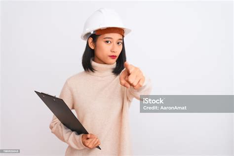 카메라와 당신에 게 손가락으로 가리키는 고립 된 흰색 배경 위에 클립 보드를 들고 헬멧을 착용 하는 중국 건축가 여자 손 기호