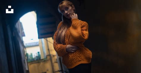 갈색 니트 스웨터와 검은 바지를 입은 여자가 복도에 서 있다 사진 Unsplash의 무료 시원하다 이미지