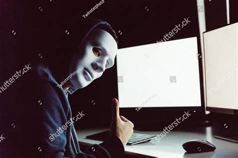 Masked And Anonymous Hacker Under Hood Giving Thumbs Up While Using A