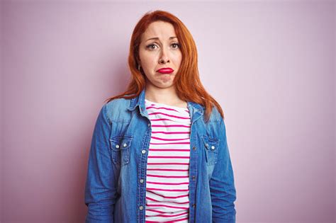 데님 셔츠와 스트라이프 티셔츠를 입고 고립 된 분홍색 배경에 우울한 아름다운 빨간 머리 여자는 분노와 두려워 울고 고민에 대한 걱정 슬픈 표정 T 셔츠에 대한 스톡 사진 및
