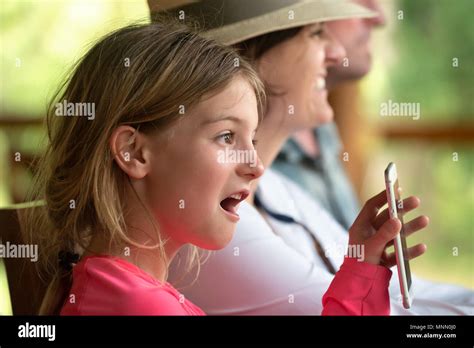 Girl Showing Cell Phone To Someone Across The Table At A Restaurant In