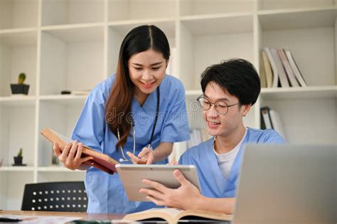 Two Asian Medical Students Are Talking Using Tablet And Researching