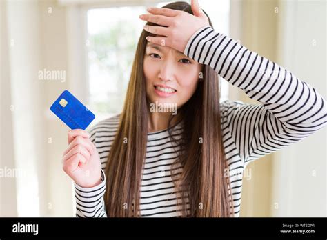 Beautiful Asian Woman Holding Credit Card Stressed With Hand On Head