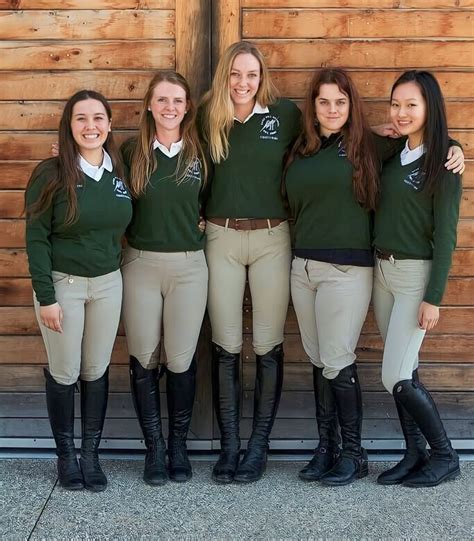 Four Girls In Green Shirts And Riding Boots Posing For The Camera With Their Arms Around Each Other