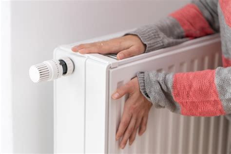Premium Photo A Woman Touches A Cold Radiator Of A Home Heater And Increases The Heating Power