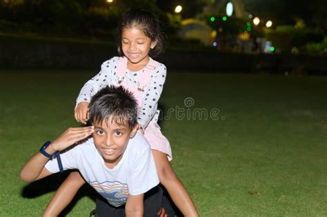 Indian Brother And Sister Playing Together In The Park At Night Stock