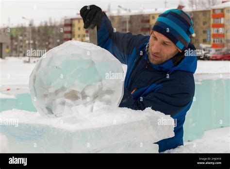 A Sculptor Carves A Round Ice Ball Out Of A Block Of Ice With A Chisel