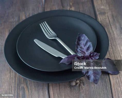 검은 접시가있는 테이블 설정 나무 테이블에 바질 잎이있는 실버 칼 붙이 식사 설정 0명에 대한 스톡 사진 및 기타 이미지 0
