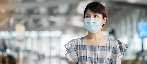 Mulher adulta jovem usando máscara facial no terminal do aeroporto proteção contra infecção por