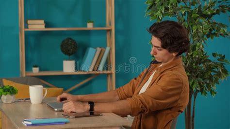 Medium Shot Capturing A Man Working On A Laptop In His Home Office And