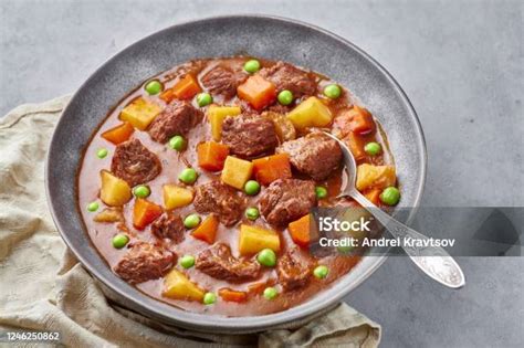 콘크리트 배경에 매트 회색 그릇에 아일랜드어 쇠고기 스튜 감자 당근 완두콩 허브를 곁들인 쇠고기 또는 양고기 고기를 곁들인 스튜 전통적인 미국 및 유럽 음식 저녁 식사 미어