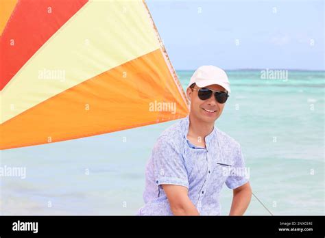 Portrait Of Happy Man In Baseball Cap And Sunglasses Under Sail On Sea