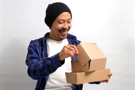 Premium Photo An Asian Man Smiles While Peering Into A Package Parcel