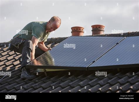 Man Installing Rooftop Solar Panel Array In A Domestic Solar Panel