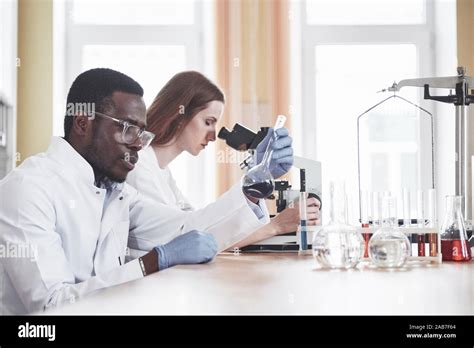 Scientists Work Closely With The Microscope In The Laboratory By Conducting Experiments And