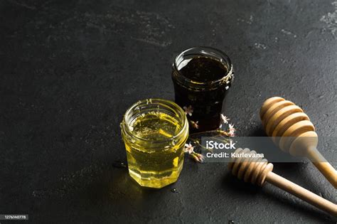 검은 돌 배경 위에 두 개의 나무 숟가락유리 항아리에 빛과 어두운 건강한 유기농 천연 꿀 0명에 대한 스톡 사진 및 기타 이미지