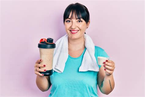 Young Hispanic Woman Wearing Sportswear Holding Water Bottle Smiling