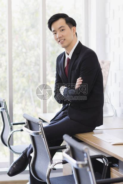亚洲商人坐在桌子上摆姿势高清图片下载 正版图片503982655 摄图网