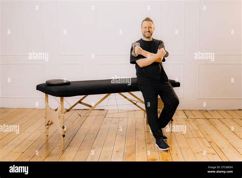 Full Length Portrait Of A Male Masseur Standing Behind A Professional