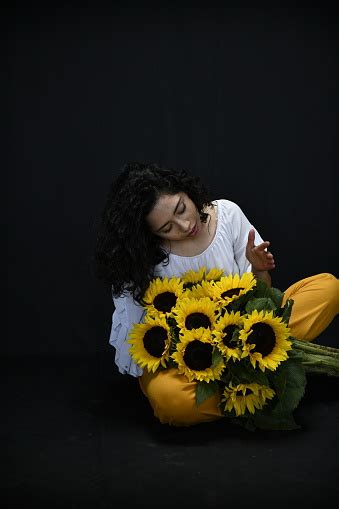 검은 배경 앞에서 해바라기와 함께 포즈를 취하는 히스패닉 여성의 세로 사진 명랑한에 대한 스톡 사진 및 기타 이미지 명랑한