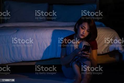 우울한 젊은 아름다운 아시아 여성은 스마트 폰을보고 침실 바닥에 혼자 앉아 스트레스 불면증 슬픈 여자는 삶의 문제를 가지고 정신