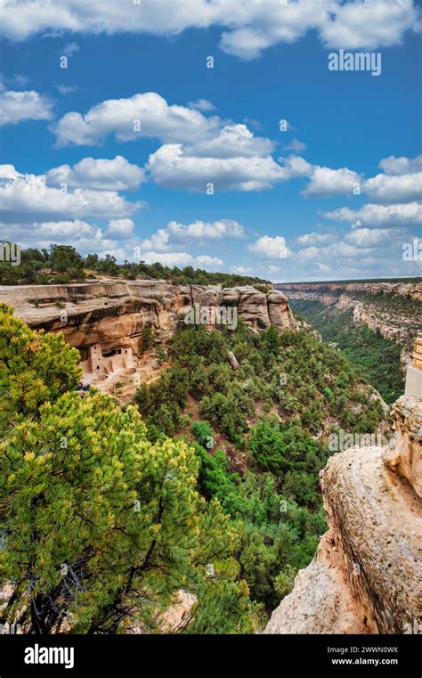 A Lush Green Valley With Historic Cliffside Dwellings Nestled Within
