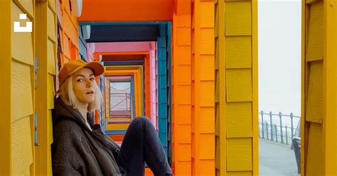 Woman In Brown Jacket And Blue Denim Jeans Sitting On Yellow Wooden