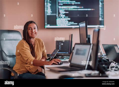 A Businesswoman Sitting In A Programmers Office Surrounded By Computers Showing Her Expertise