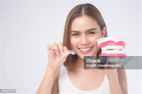 흰색 배경 스튜디오 치과 의료 및 치열 교정 개념을 통해 Invisalign 중괄호와 인공 치과 모델을 들고 젊은 미소 여자 치아 교정장치에 대한 스톡 사진 및 기타 이미지