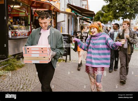 Smiling Non Binary Person Holding Stack Of Pizza Boxes While Walking