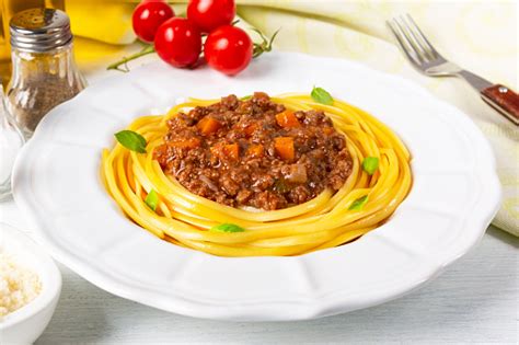 파스타와 소스 볼로냐 파 르 마 치즈 토마토의 향미료와 바 질입니다 에 백색 격판덮개 배경은 흰색 이다 이탈리아 음식입니다 가로