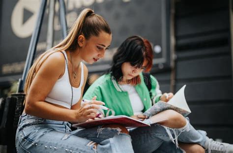 Two Casually Dressed High School Girls Studying Outdoors Discussing