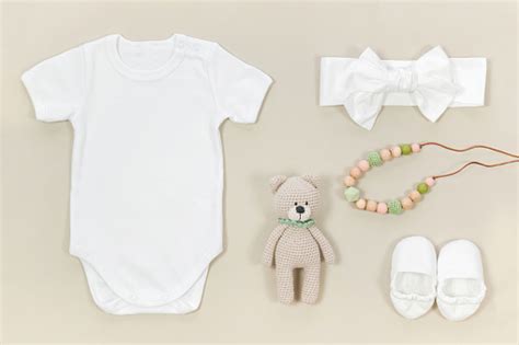 부티와 머리띠가 있는 아기 모형을 위한 흰색 바디수트 파스텔 베이지색 배경에 어린이 장난감 치발기 구슬 에코 스타일의 액세서리가 있는 아기 옷 모형 0명에 대한 스톡 사진