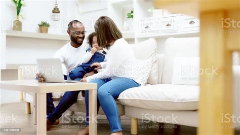 행복한 아프리카 가족 부모와 어린 아이들은 함께 컴퓨터 노트북을 사용하는 것을 즐긴다 소파에 앉아 기술 중독 커플과 집에서