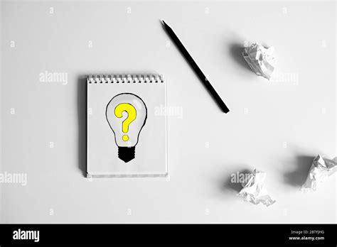 Pen And Crumpled Paper Near Notepad With Drawing Of Bulb With Question