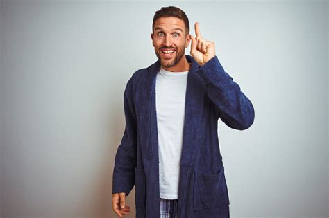 편안한 잠옷과 가운을 입고 아침에 고립 된 배경을 통해 성공적인 아이디어로 손가락을 가리키는 젊은 남자 종료하고 행복 넘버 원