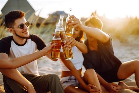 Premium Photo Young People Sitting Together At Beach Drinking Beer