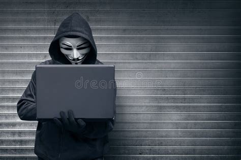 Hooded Hacker With Mask Holding Laptop While Typing Editorial Stock