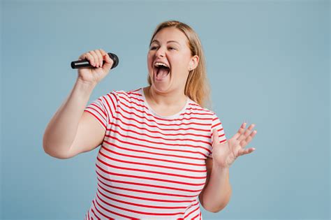 젊은 플러스 사이즈 백인 여성이 파란색에 고립 된 마이크와 함께 감정적으로 노래합니다 30 34세에 대한 스톡 사진 및 기타 이미지 30 34세 가수 개념 Istock