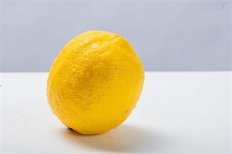 밝은 배경의 흰색 표면에 전체 및 반으로 자른 노란색 레몬을 배치하여 육즙이 많은 감귤류 질감 씨앗 및 신선한 열대 과일의 생생한 자연색을 보여줍니다 겉껍질에 대한 스톡