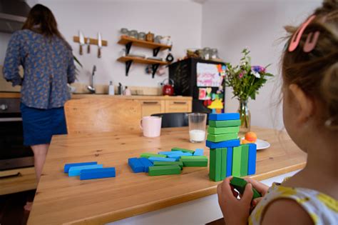 집에서 어린 딸이 화려한 나무 블록으로 부엌 테이블 뒤에서 놀고있는 동안 점심을 요리하는 어머니 놀기에 대한 스톡 사진 및 기타 이미지 Istock