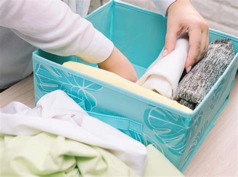 Premium Photo Woman Hands Folds Her Clothes And Puts Them In Blue Storage Box Vertical Storage