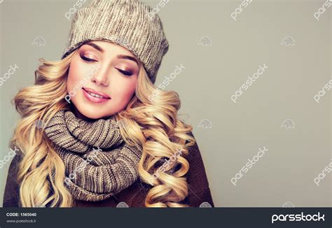پرتره زن جوان موهای بلوند لبخند جذاب با کلاه و روسری زمستانی پشمی