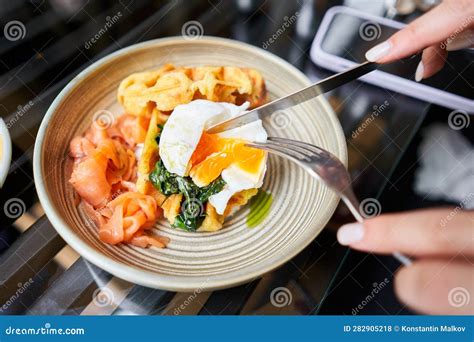 Woman Cuts Poached Egg And Yolk Flows Out Potato Waffles Avocado
