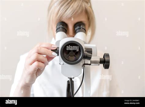 Female Blond Doctor Gynecologist Looks Through A Colposcope